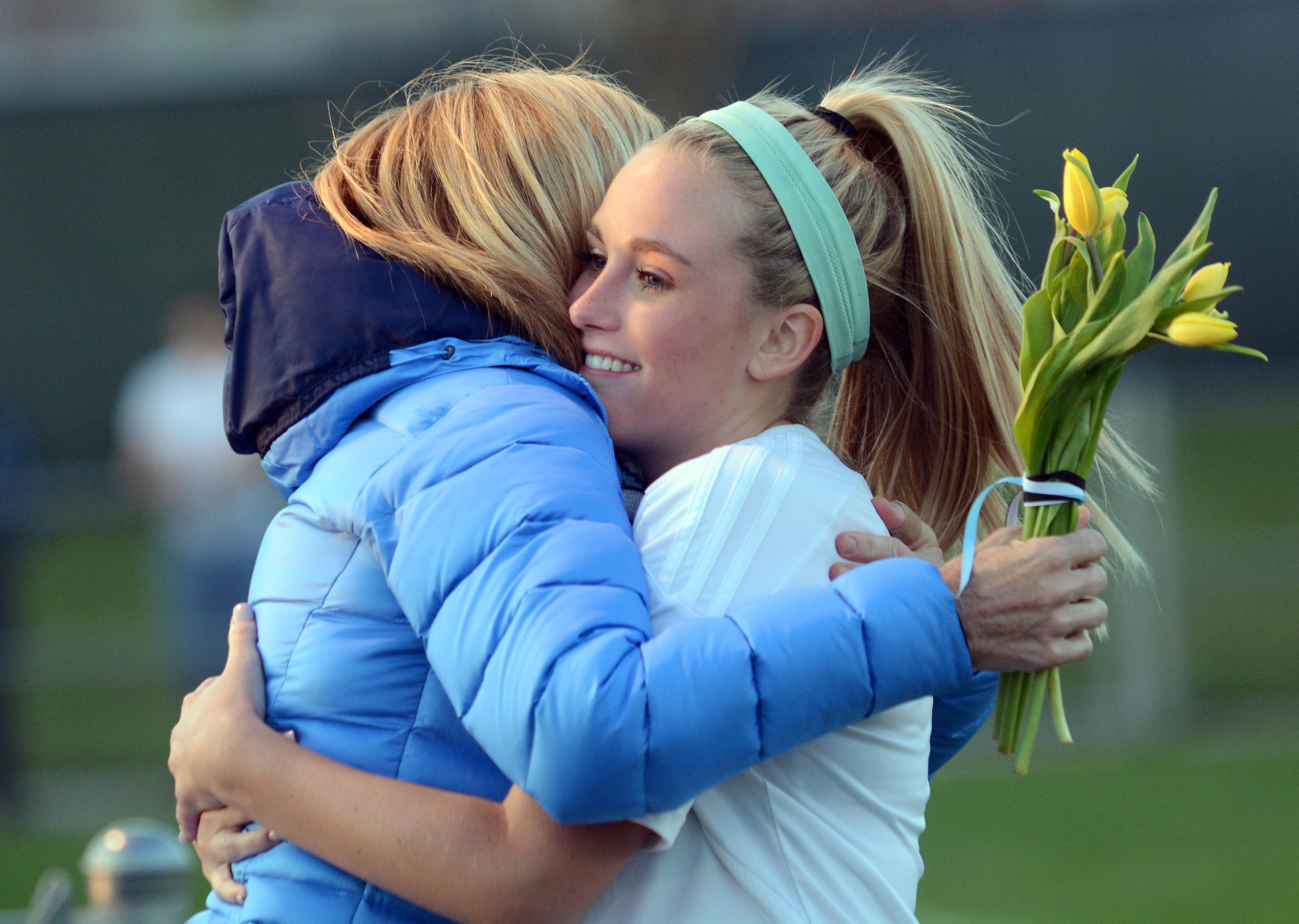 Senior Libby Legard hugs her mom after handing her flowers for senior ...